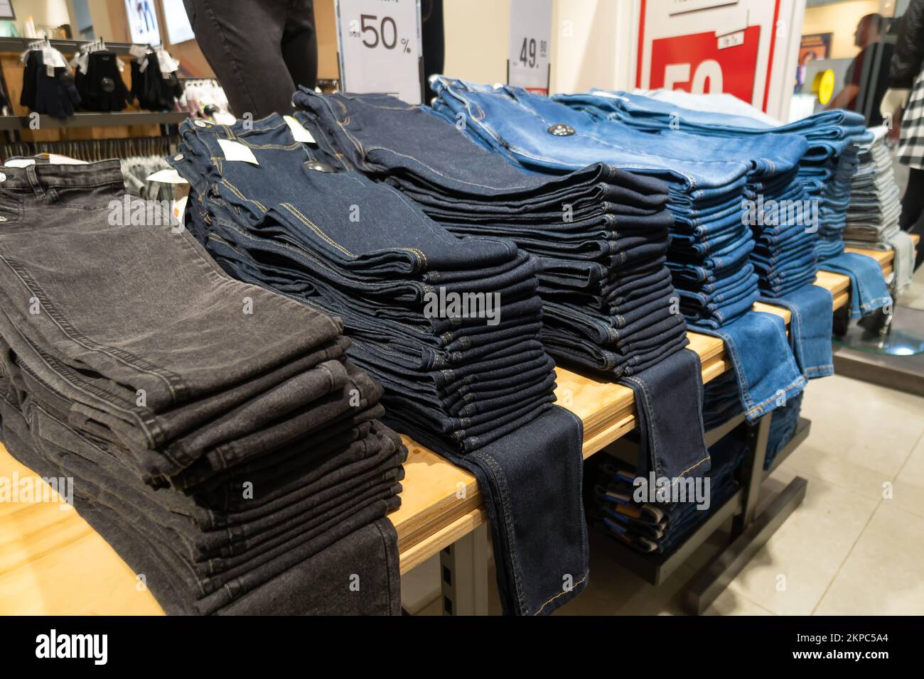 Many different jeans are on the shelf in a clothing store in a shopping ...