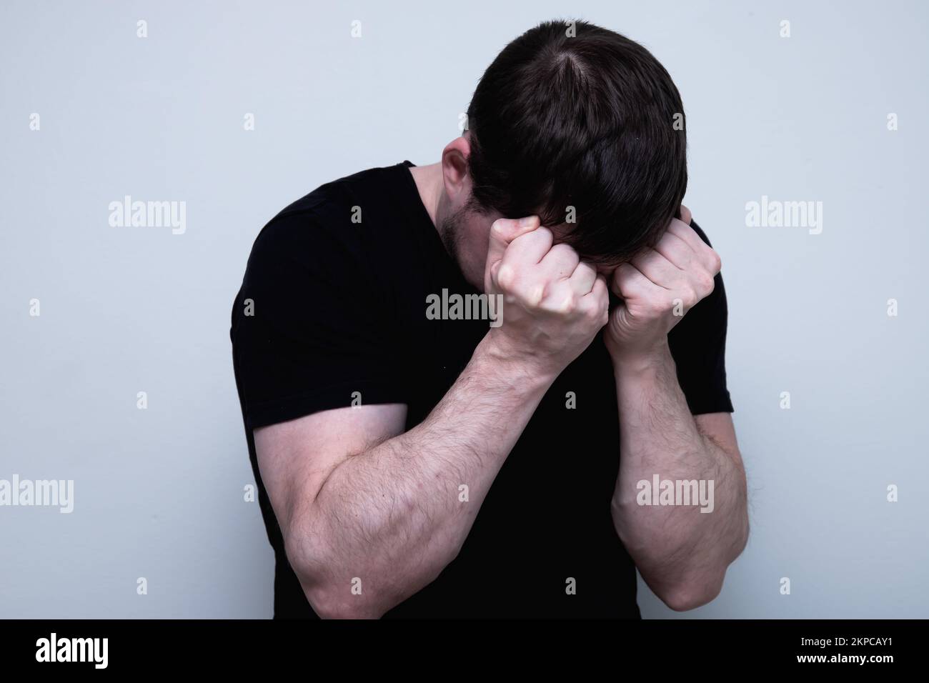 An upset guy in a black sweater hiding his face with hands Stock Photo ...