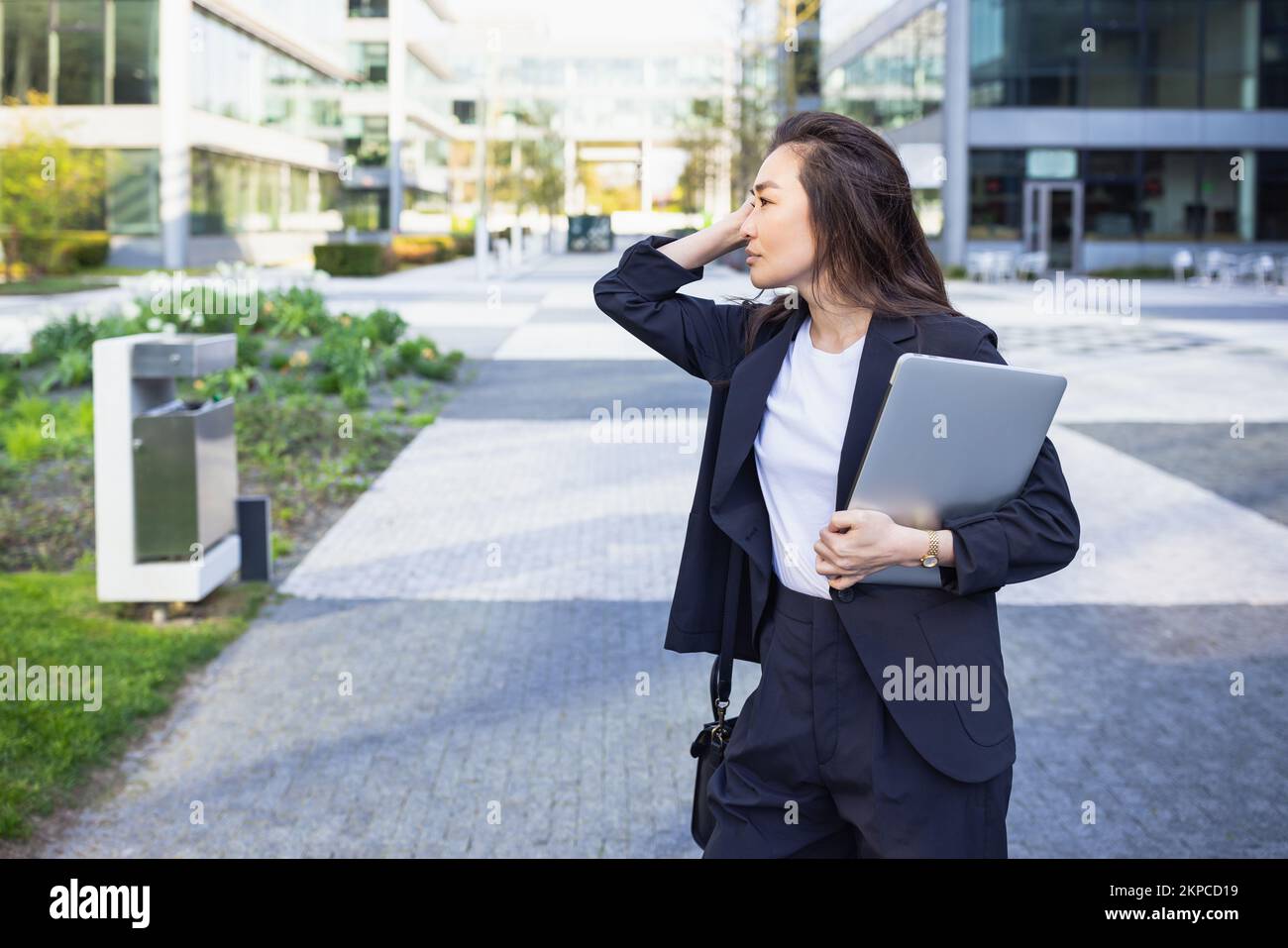 Relaxed and confident Asian business woman in suit holding laptop ...