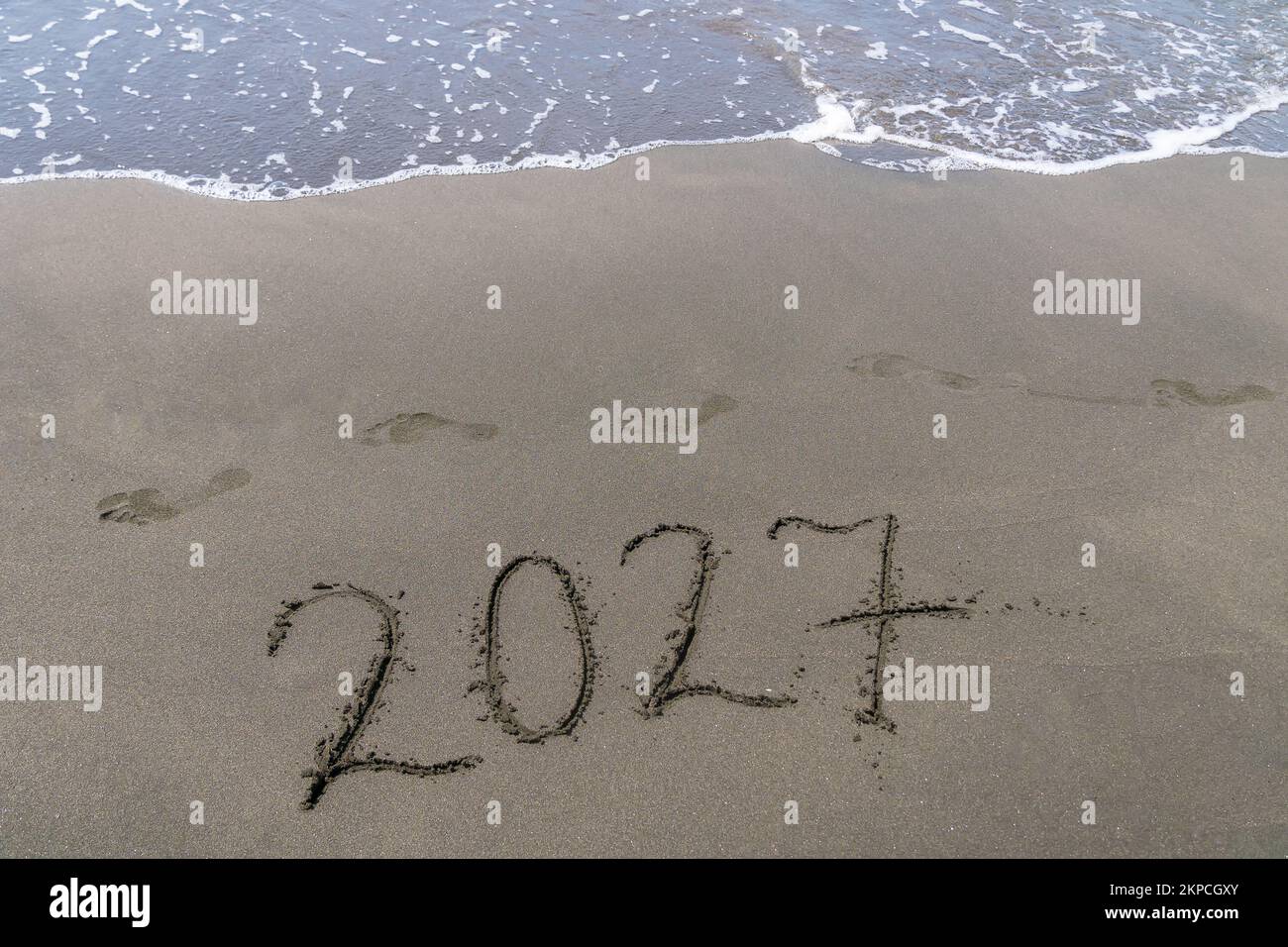 Text Happy New Year 2027 on a sandy sea beach with a small wave and ...
