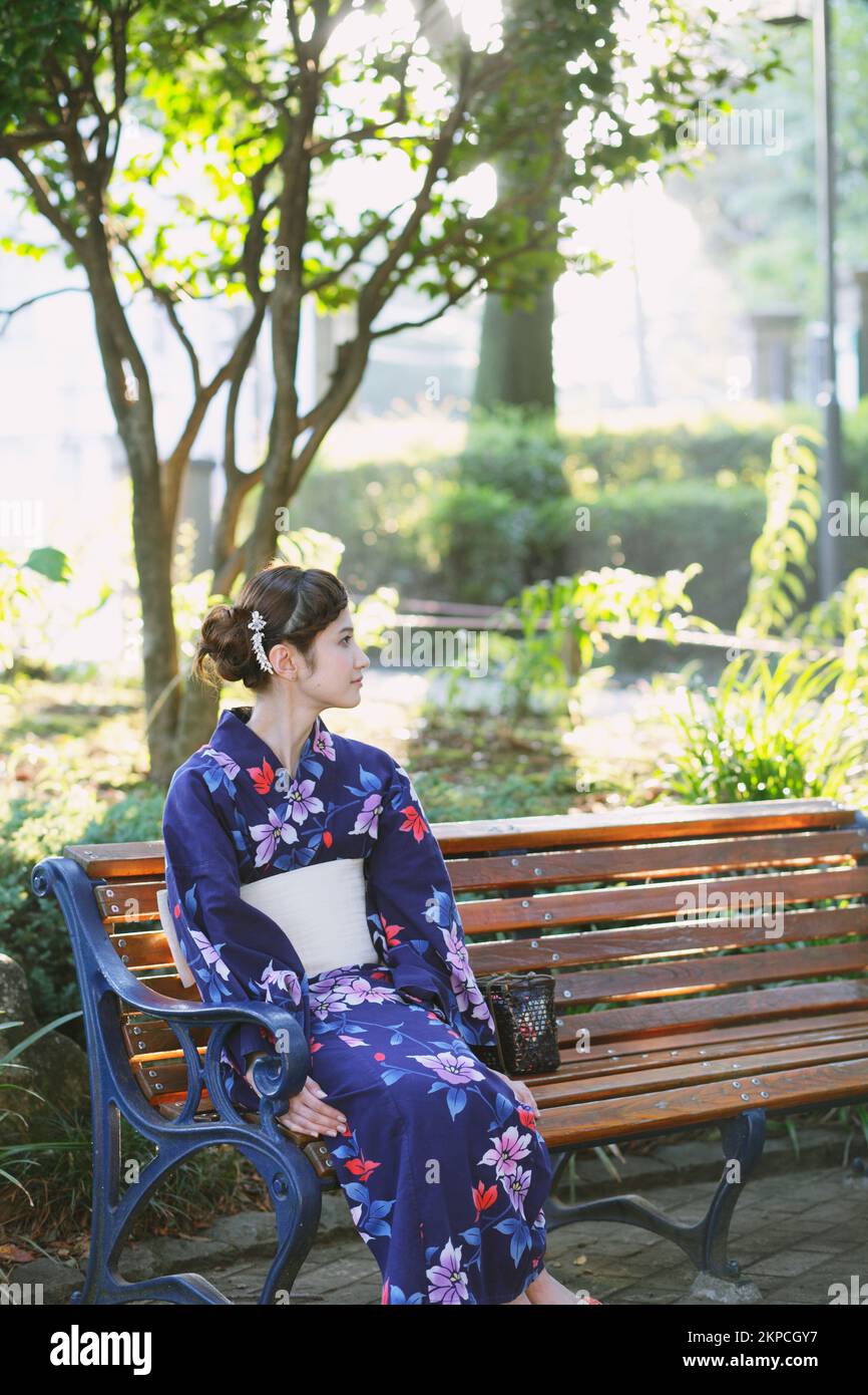 Japanese woman in a yukata sitting on a bench Stock Photo - Alamy