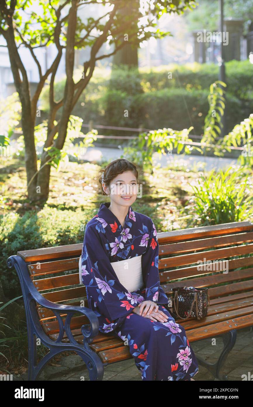 Japanese woman in a yukata sitting on a bench Stock Photo - Alamy