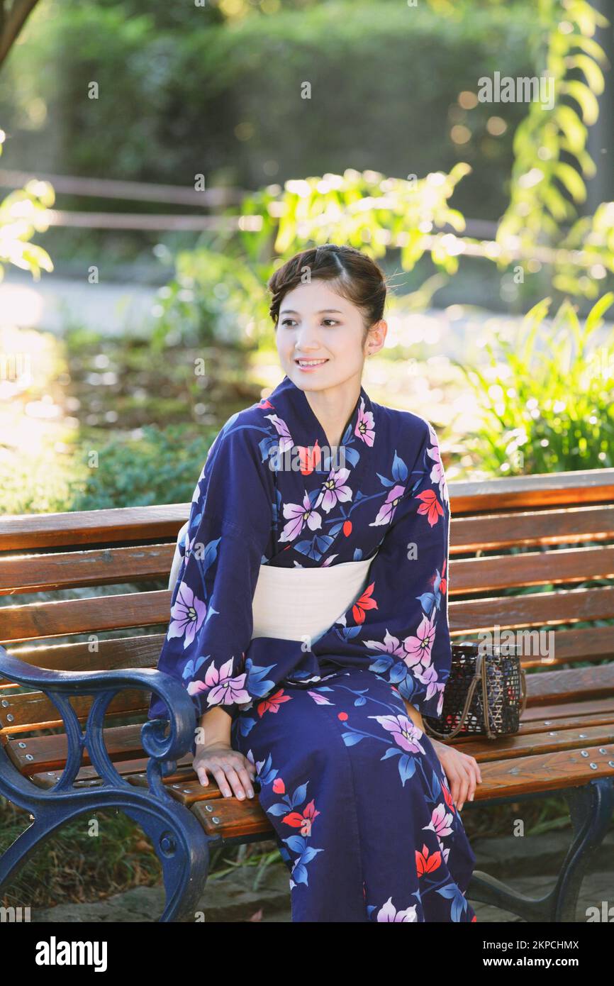 Japanese woman in a yukata sitting on a bench Stock Photo - Alamy