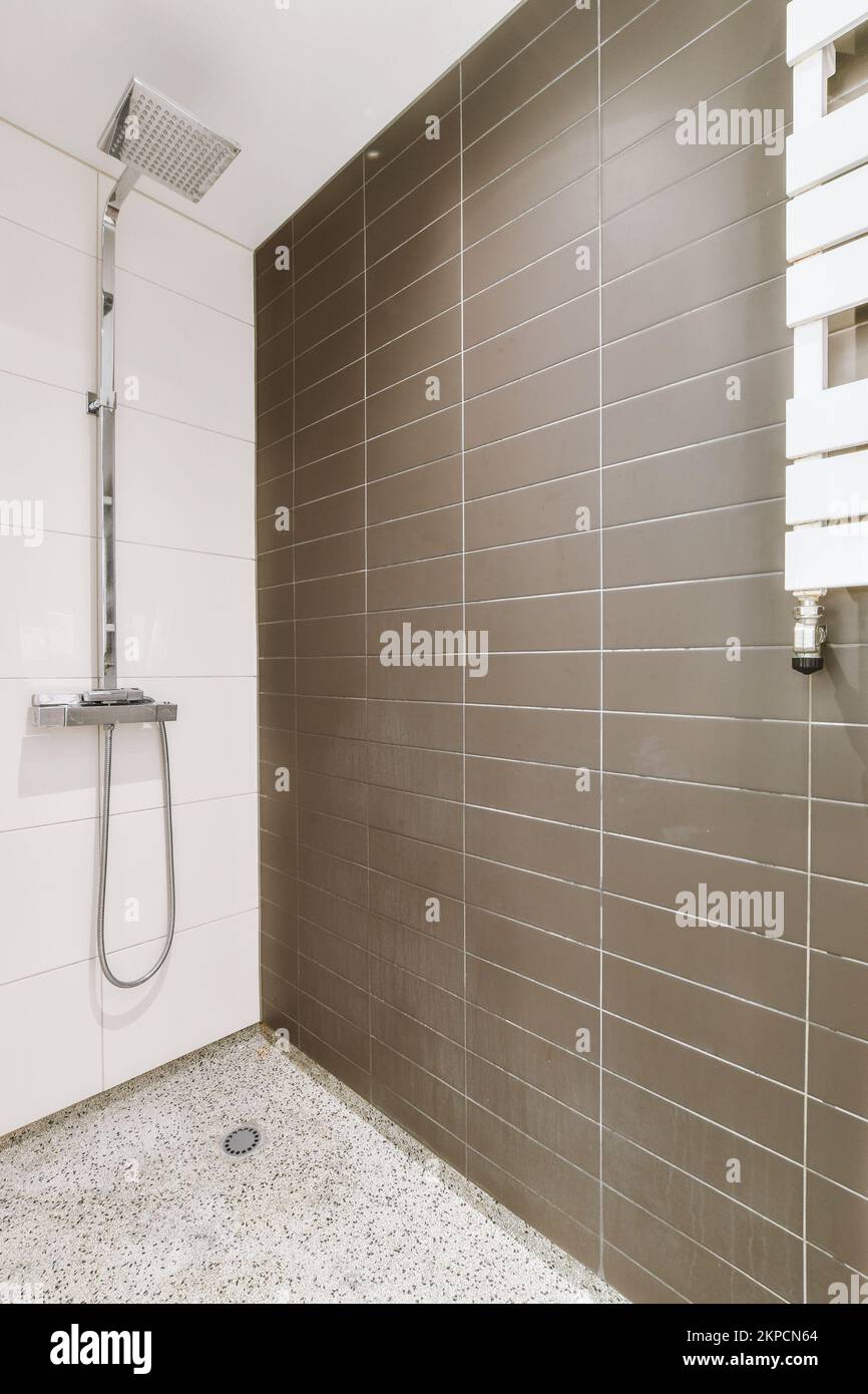 Shower faucets attached to tiled wall near glass partition and ...