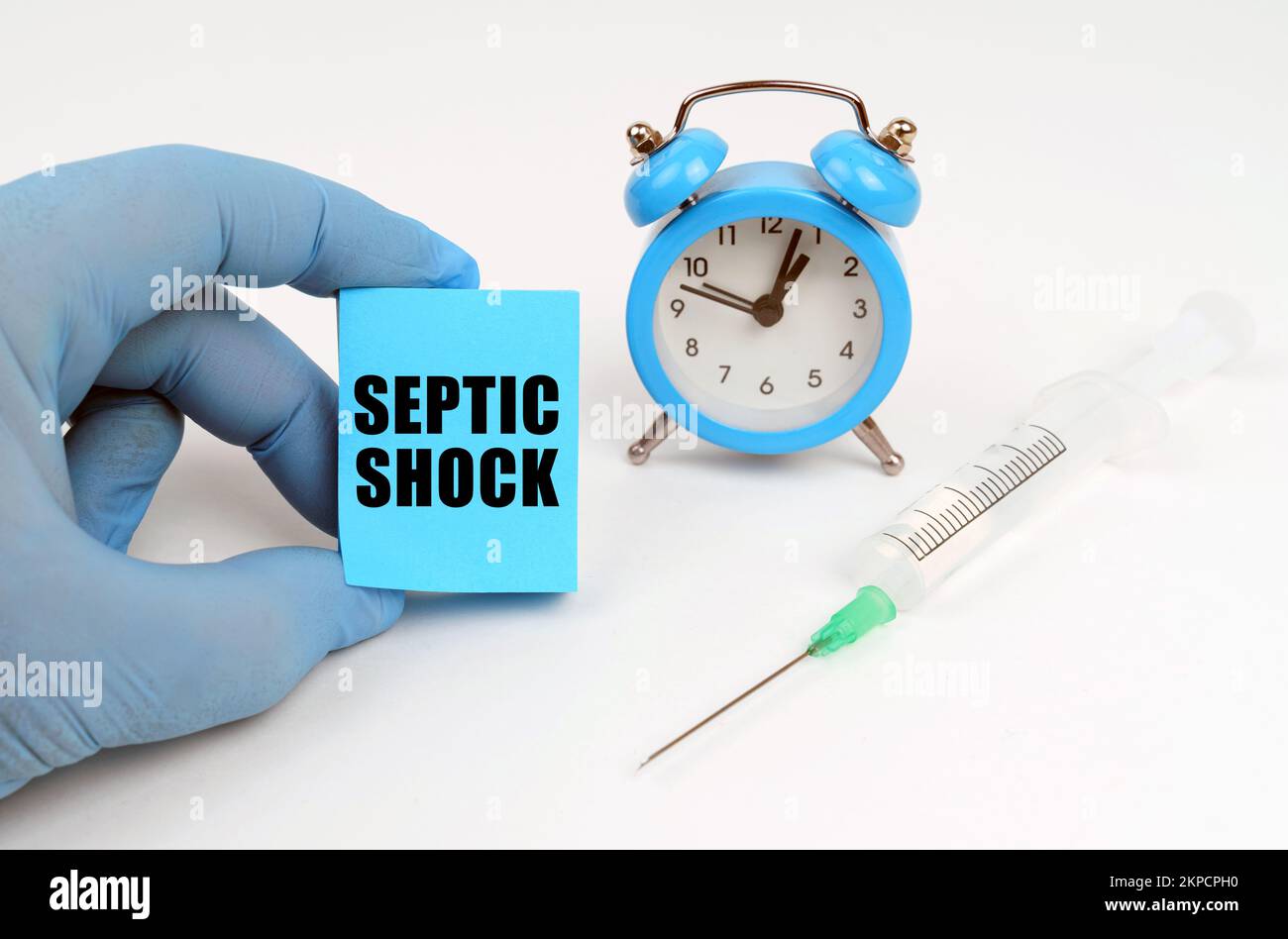 Medicine concept. On the table is a syringe and an alarm clock, in his ...