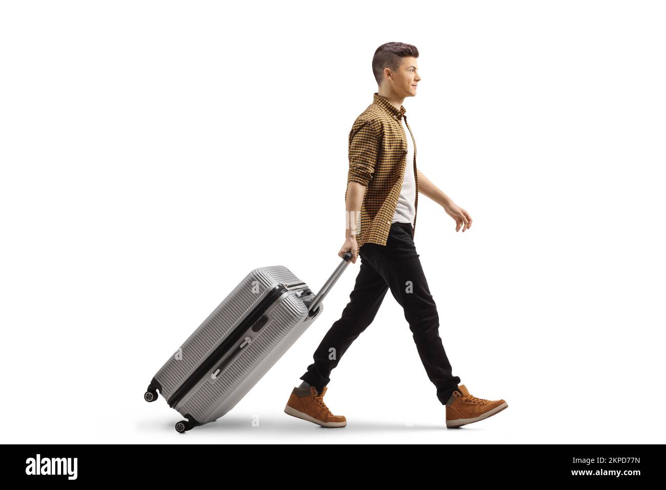 Full length profile shot of a guy walking and pulling a suitcase ...