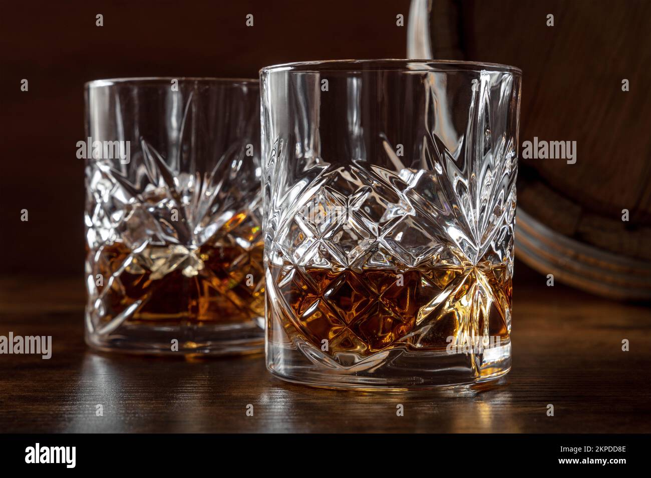 Whiskey in glasses with a barrel. Bourbon whisky and a cask on a dark ...