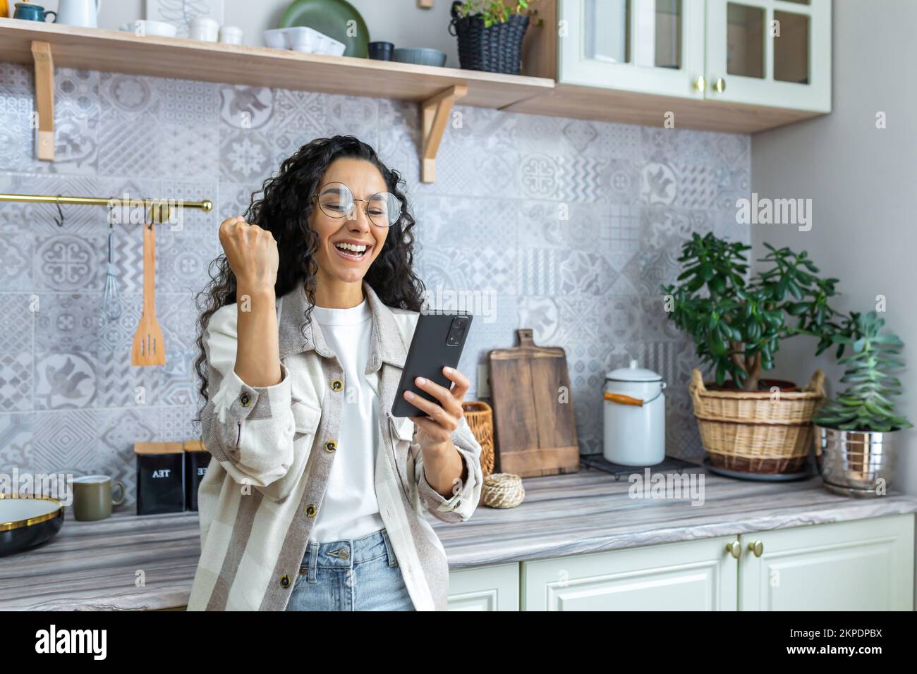 Happy beautiful young hispanic woman messing around in the kitchen at ...