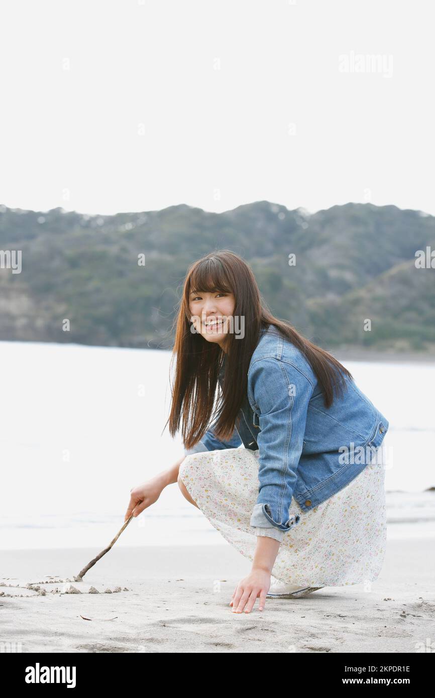 Japanese woman scribbling on the beach Stock Photo - Alamy