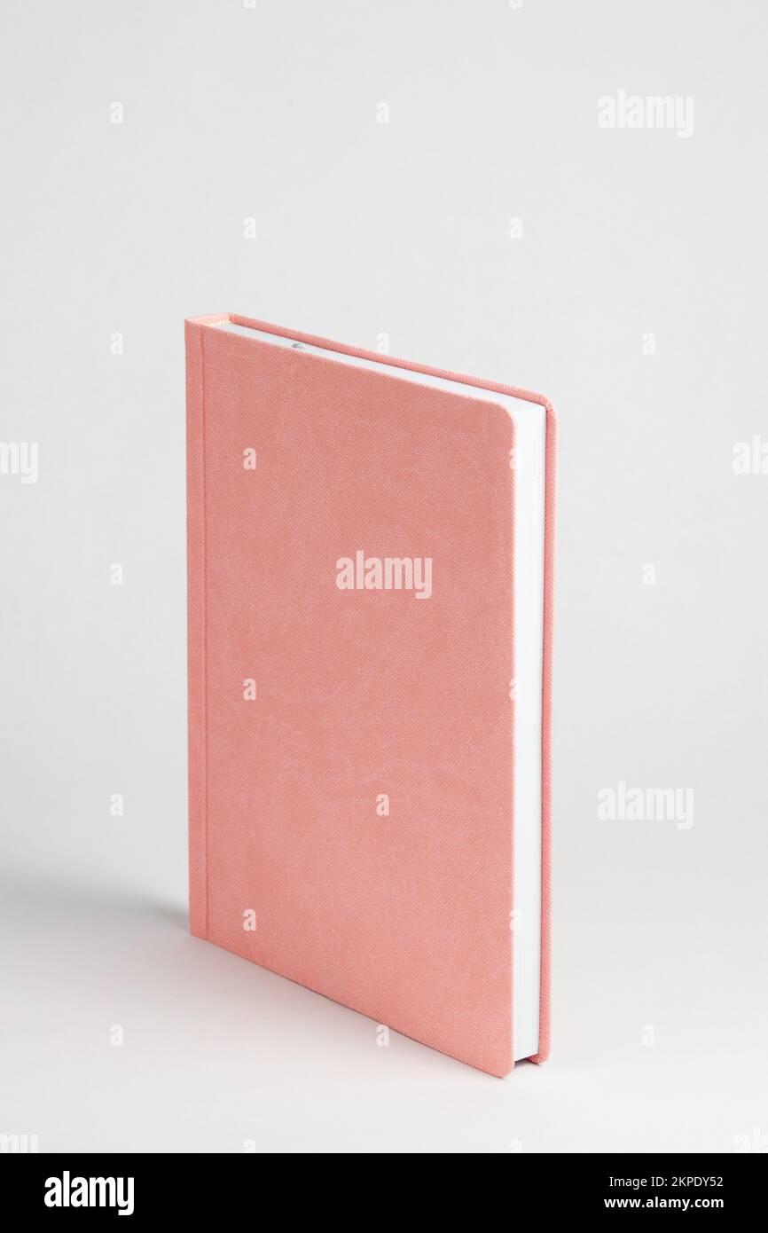 Pink diary standing on table on white background. Side view Stock Photo ...