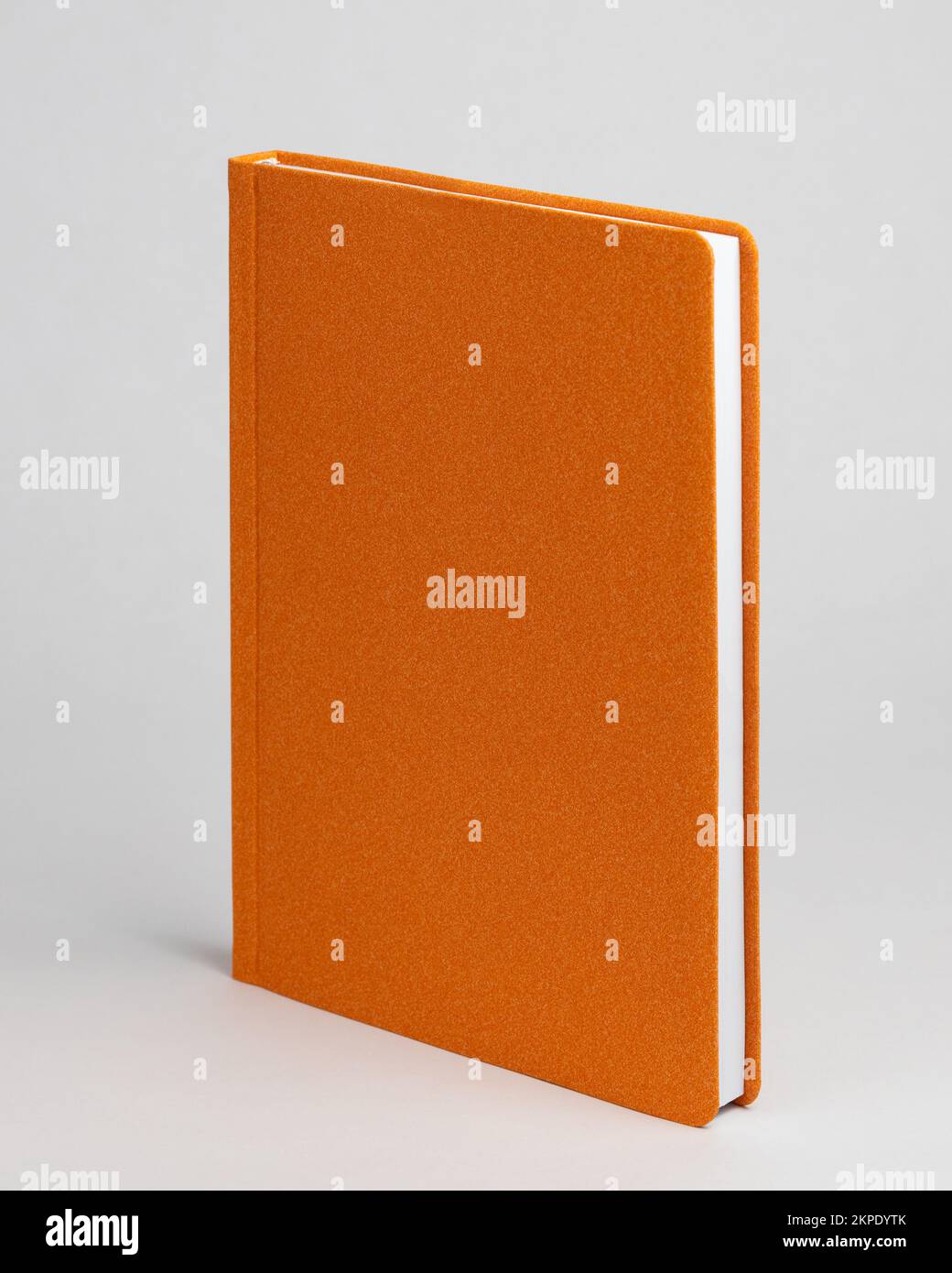 Orange diary standing on table on white background. Side view Stock Photo - Alamy