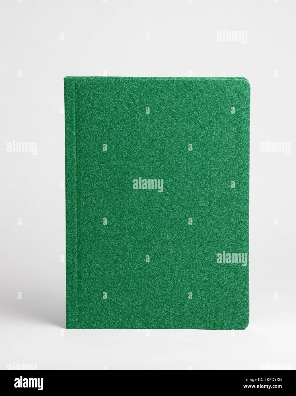 A green closed diary stands on a table on a white background. Front ...