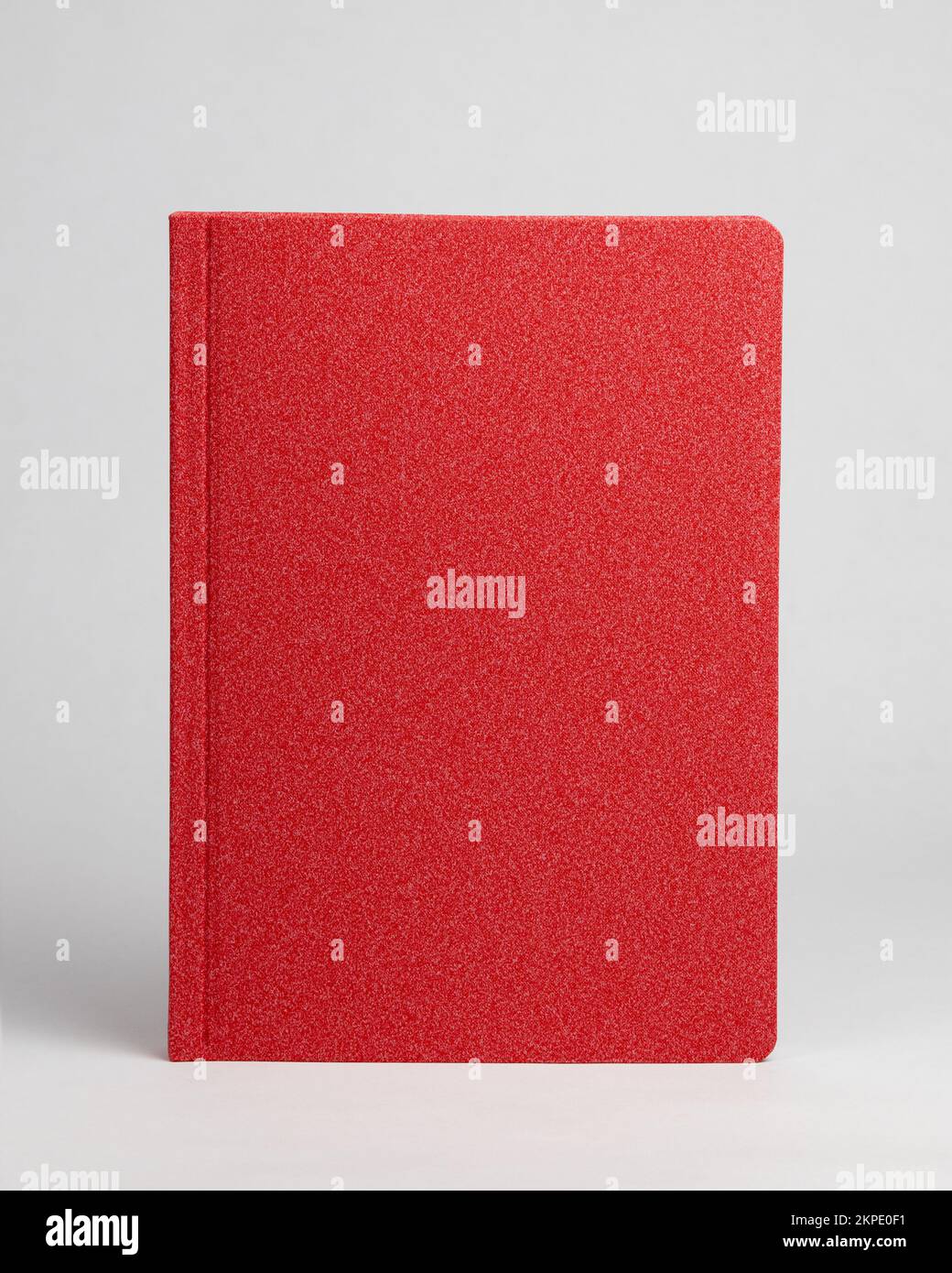 Red diary in standing view on table on white background. Frontside ...