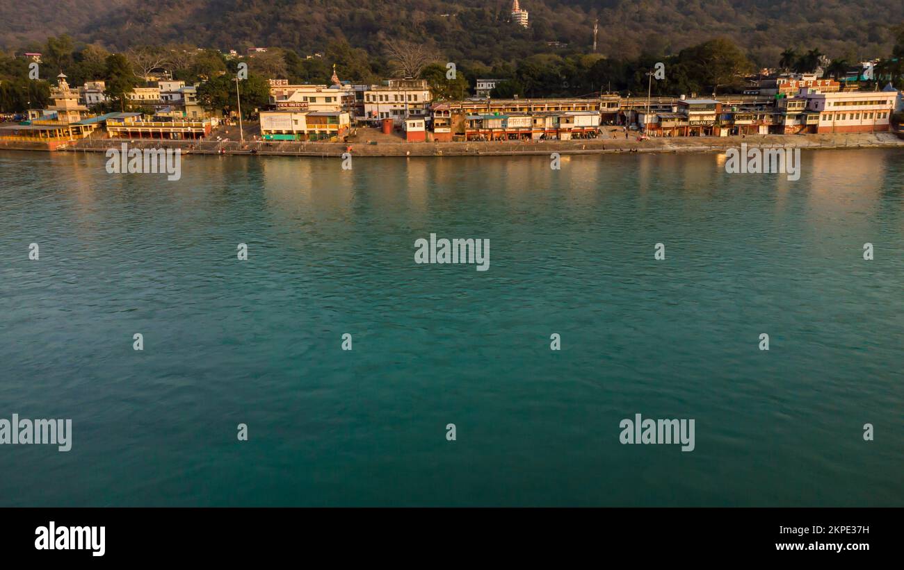 An aerial shot of a river with buildings on the shore at Rishikesh ...