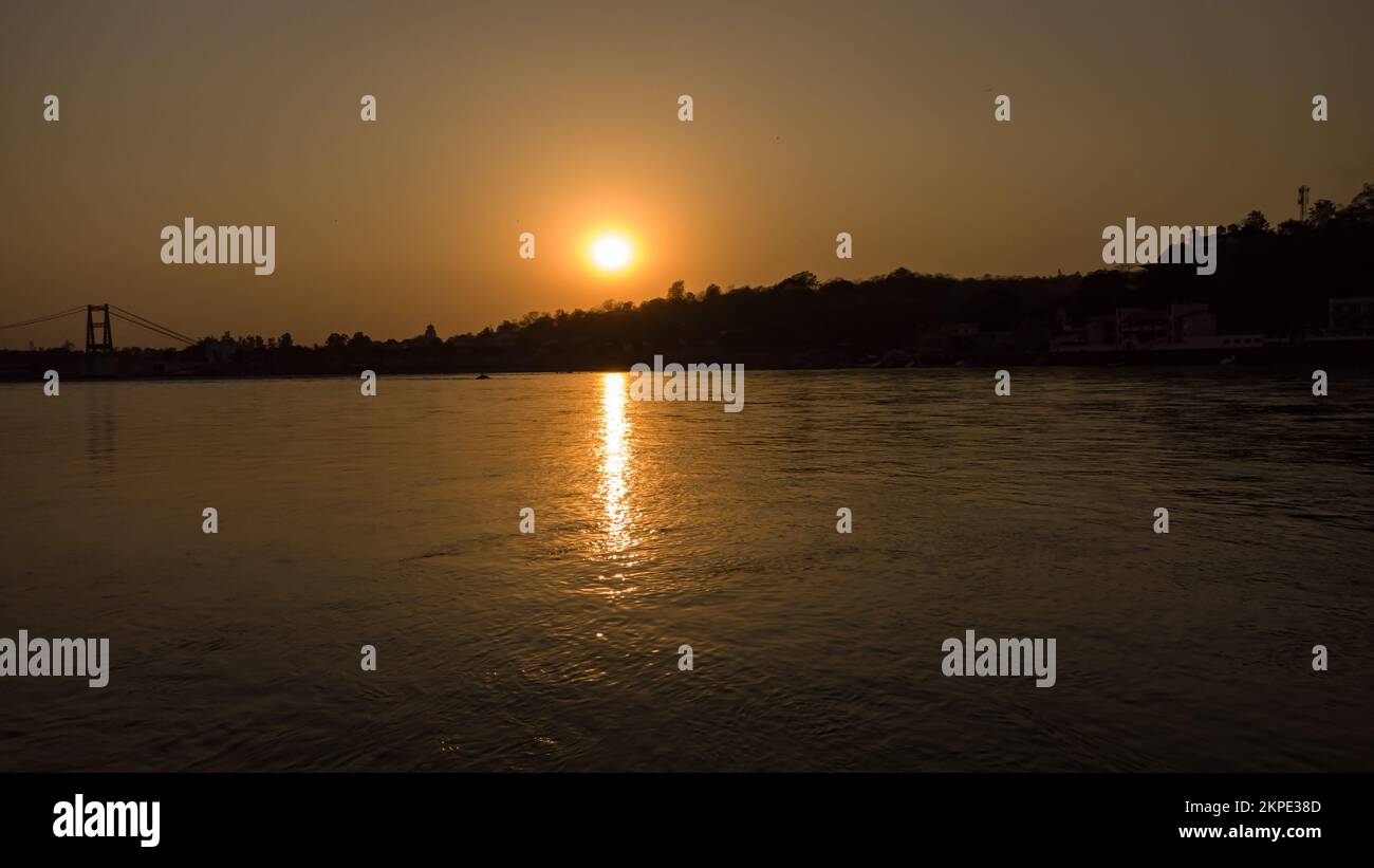 An orange sunset over a river at rishikesh uttrakhand india Stock Photo ...