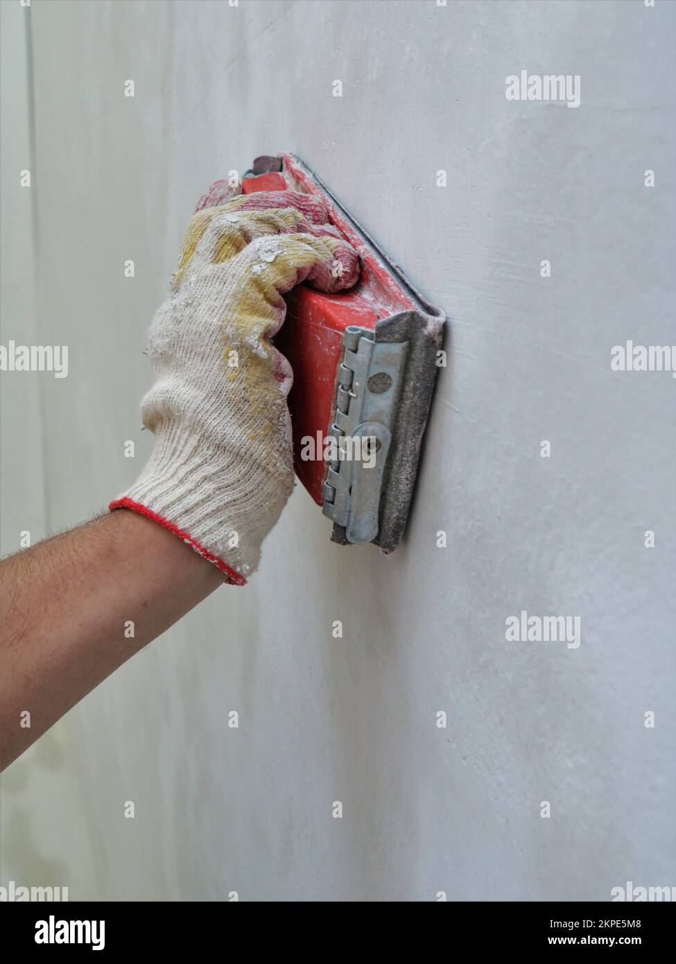 hand sander in a red case in the builder's glove hand close-up, in the ...
