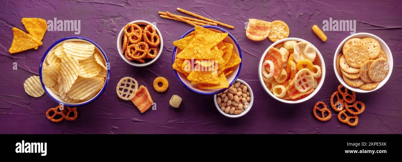 Salty snacks panorama. Party food. Potato and tortilla chips, crackers ...