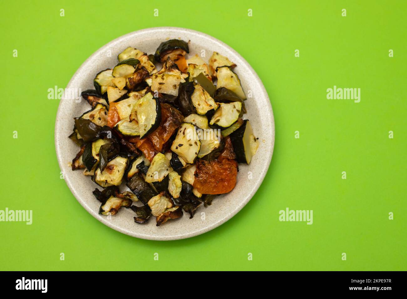 Mixed baked vegetables on light brown dish on green Stock Photo - Alamy