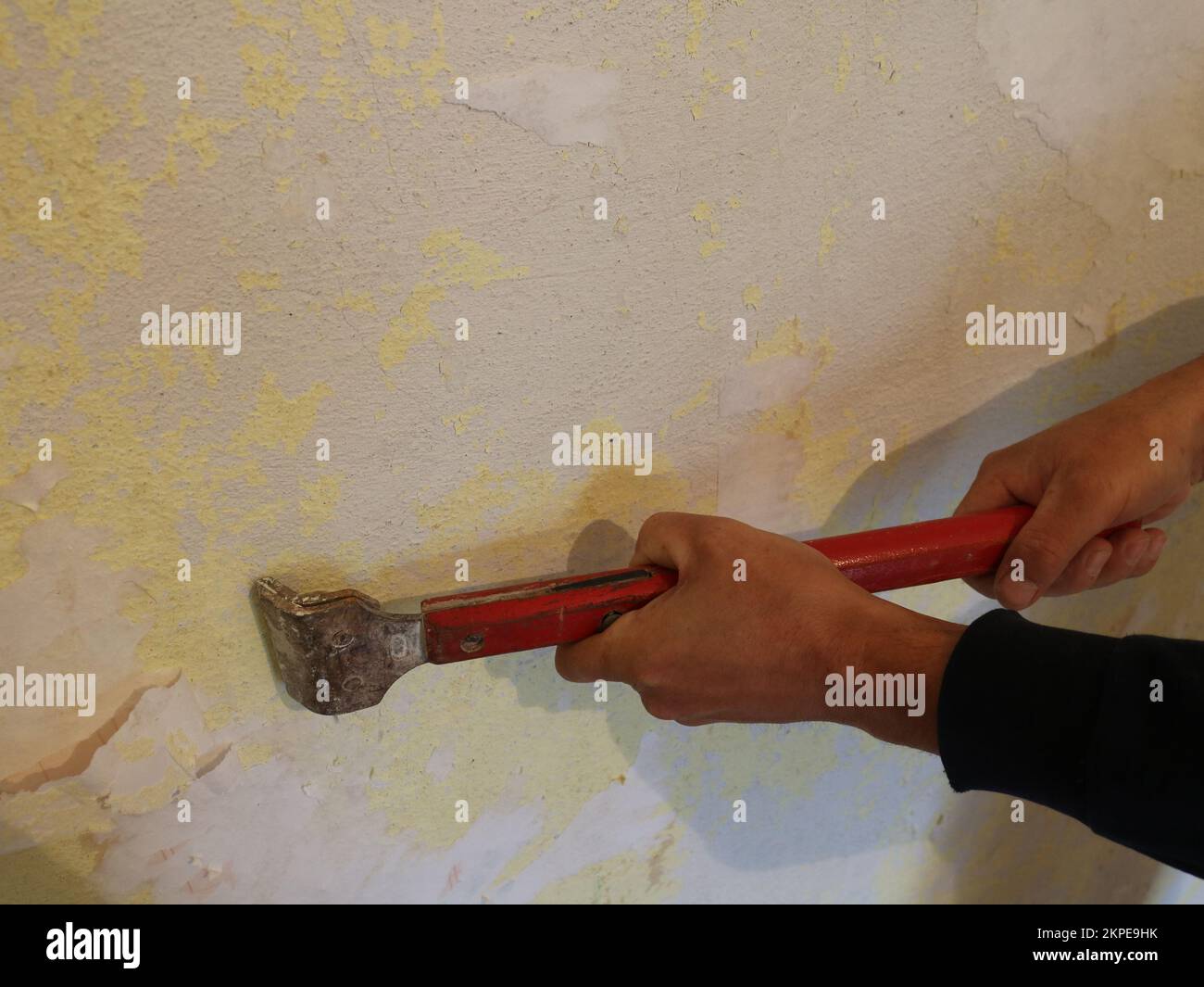 work with a narrow scraper with a long red handle to clean the wall ...