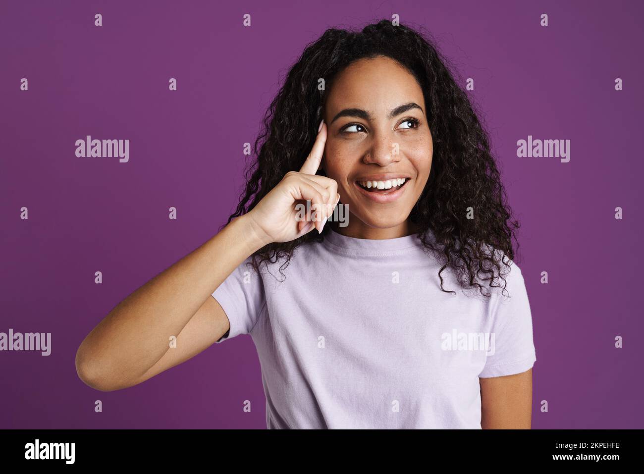 Young black woman smiling and pointing finger at her temple isolated ...