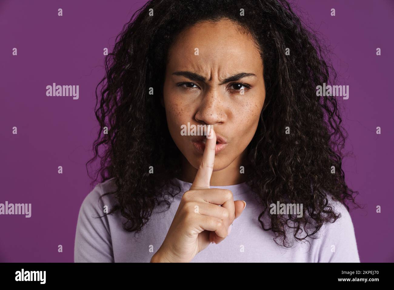 Young black woman frowning while making silence gesture isolated over ...