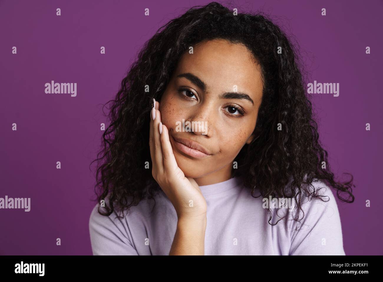 Young black woman propping up her head and looking at camera isolated ...