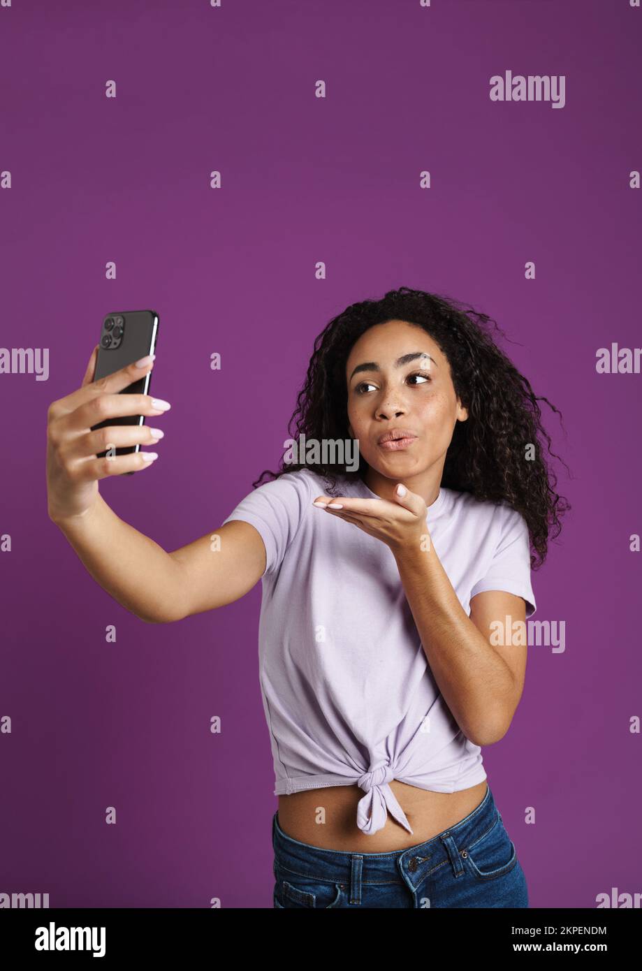 Young black woman gesturing while taking selfie on mobile phone ...