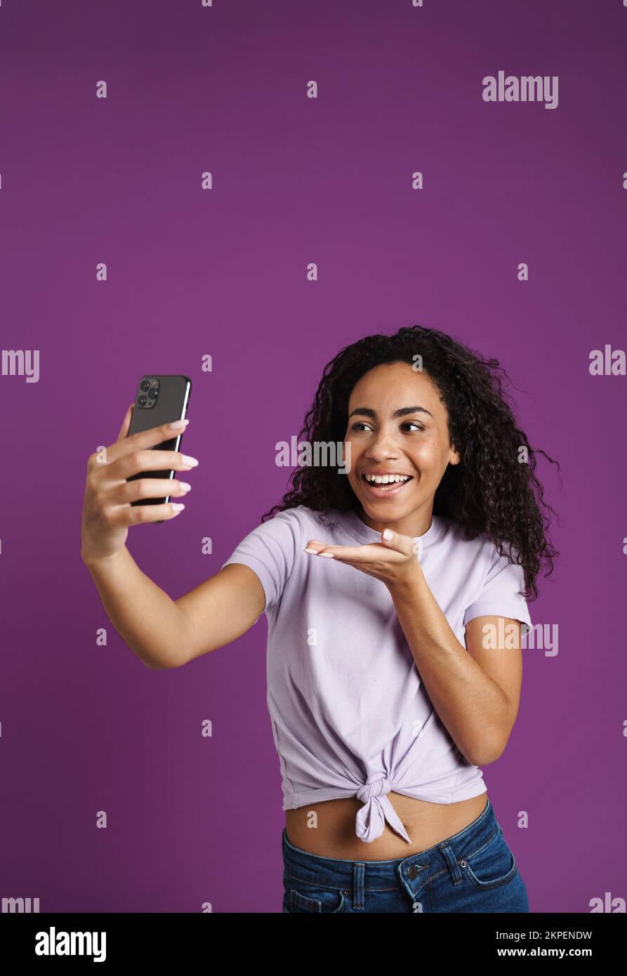 Young black woman gesturing while taking selfie on mobile phone ...