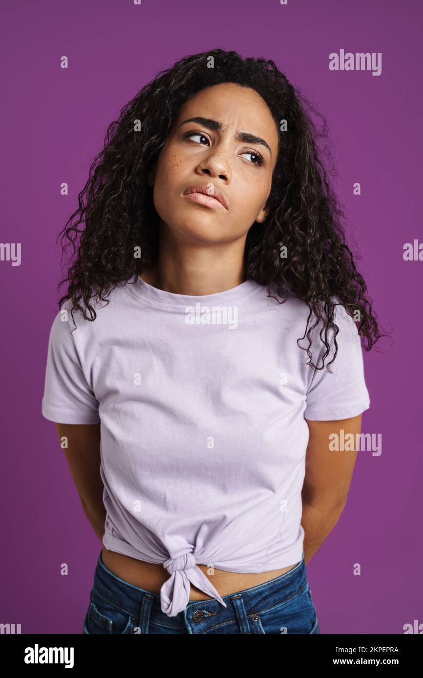 Young black woman with wavy hair frowning and looking aside isolated ...