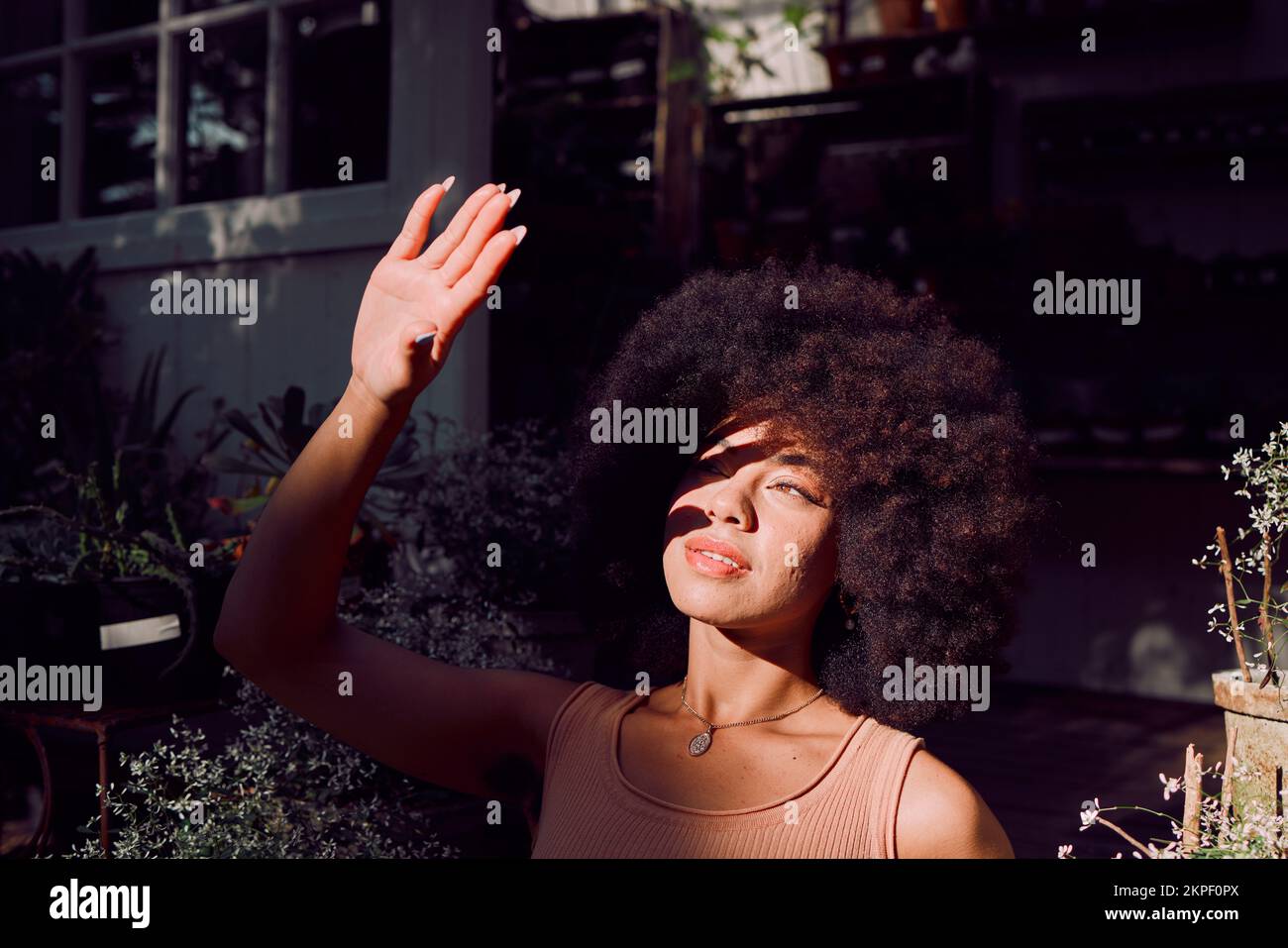 Sun, shadow and hand with a black woman covering her face from the ...