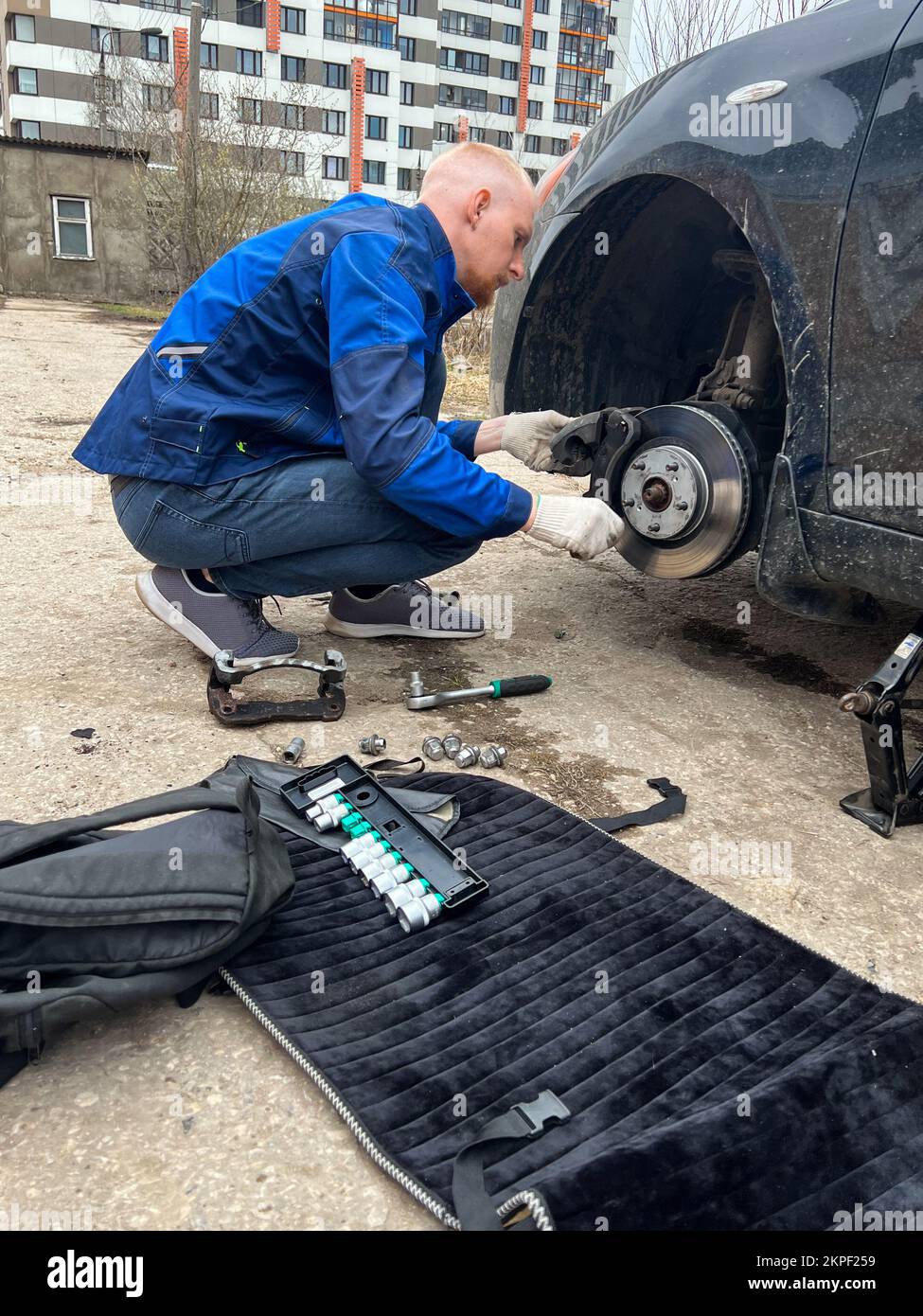 A man repairs a car on the road, replacing brake discs and pads ...