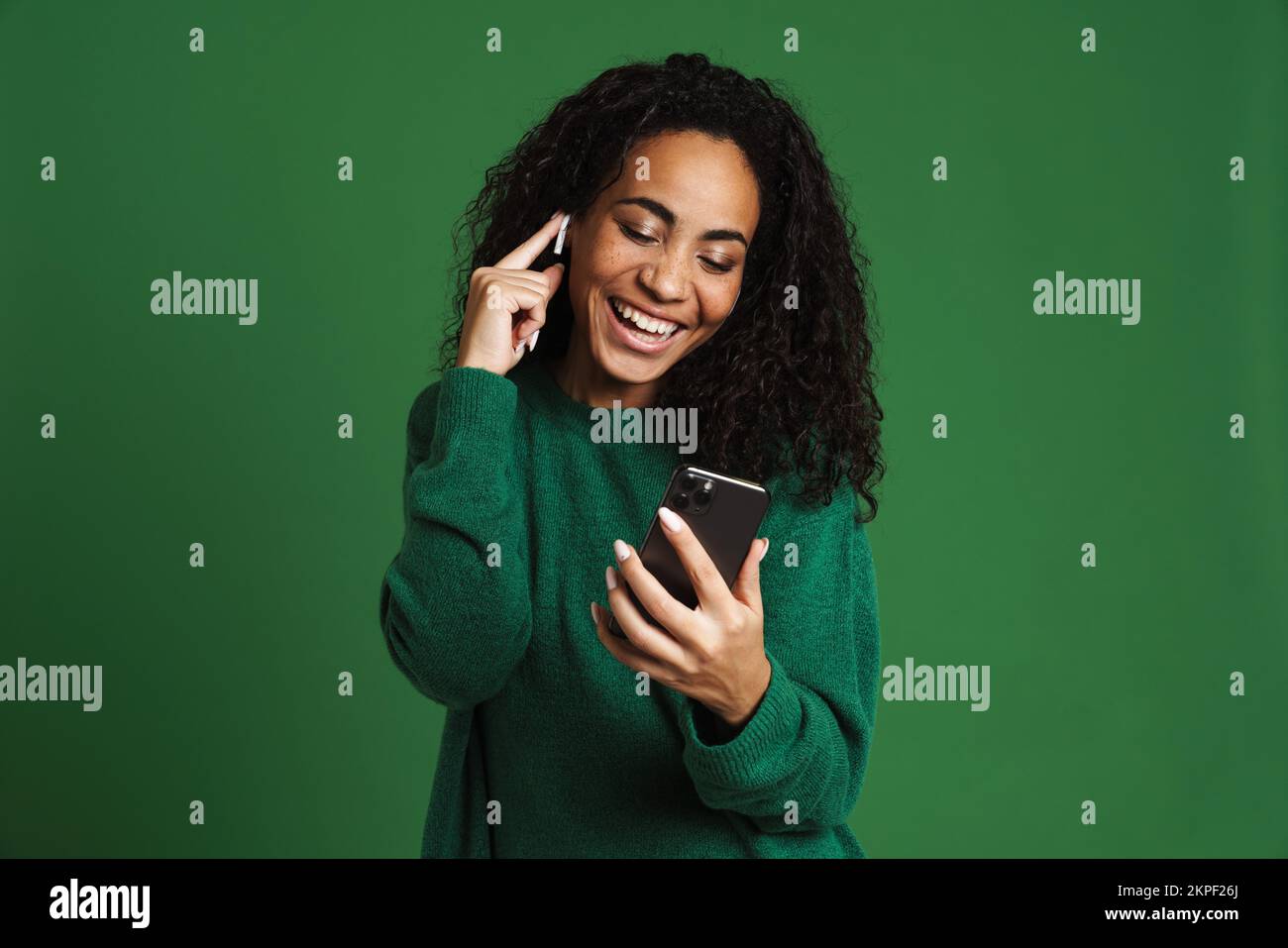 Young black woman using mobile phone while listening music isolated ...