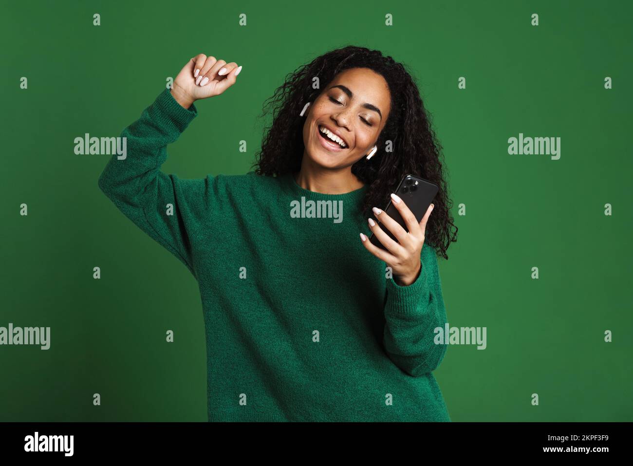 Young black woman using mobile phone while listening music isolated ...