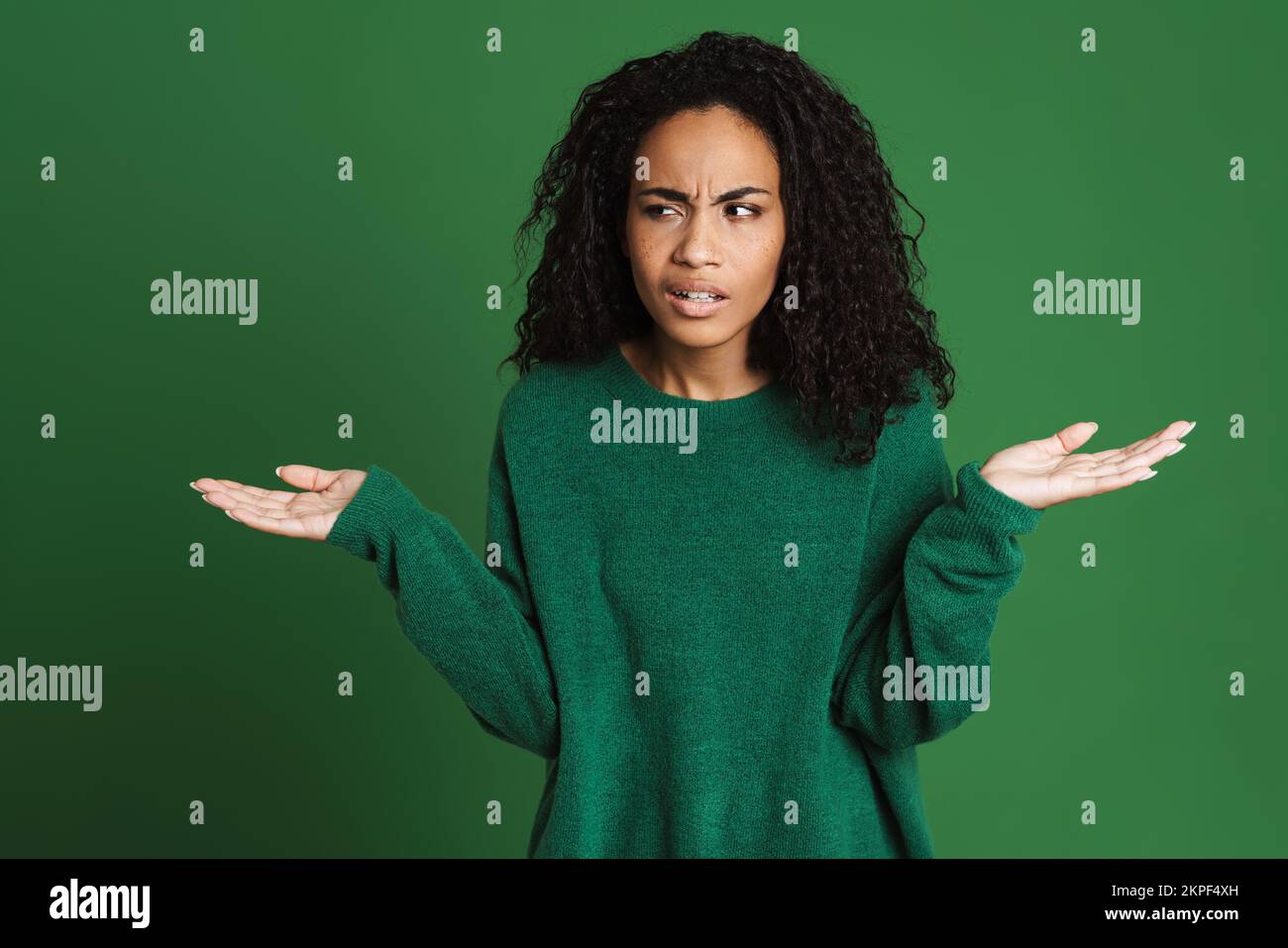 Young black woman with wavy hair frowning and holding copyspace ...
