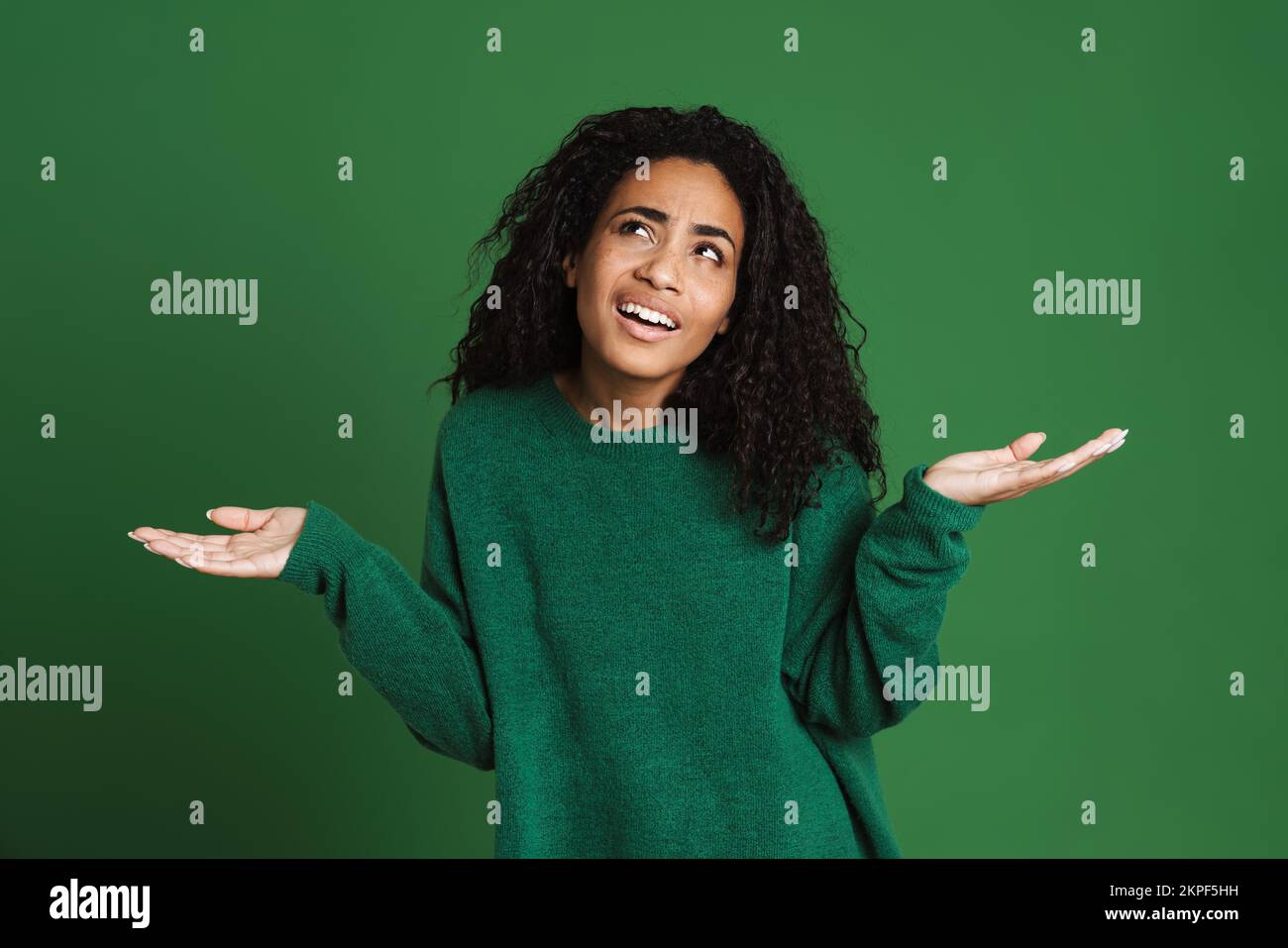 Young black woman with wavy hair frowning and holding copyspace ...