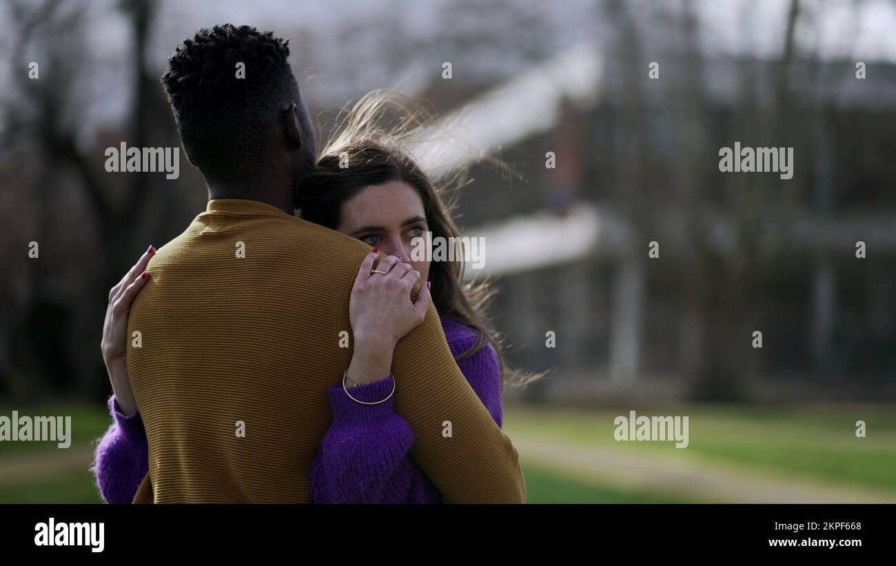 Interracial couple embrace outside. Young woman hugs partner Stock ...