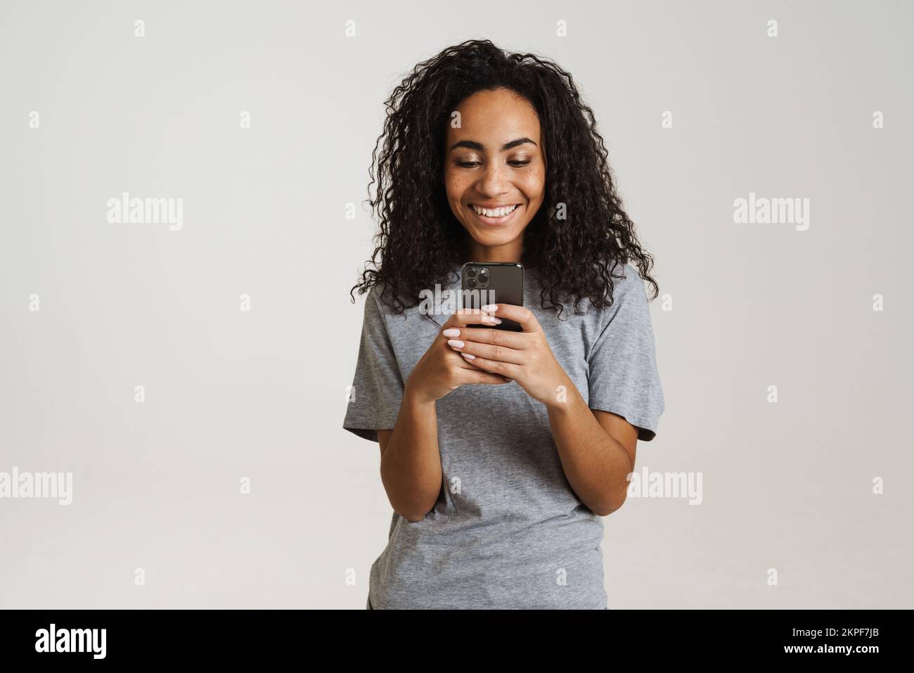 Young black woman using mobile phone and laughing isolated over white ...