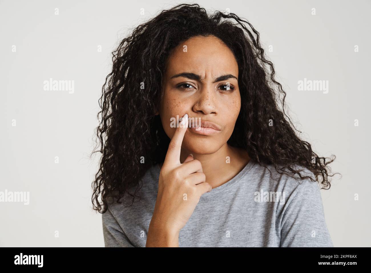 Young black woman with wavy hair frowning and looking at camera ...