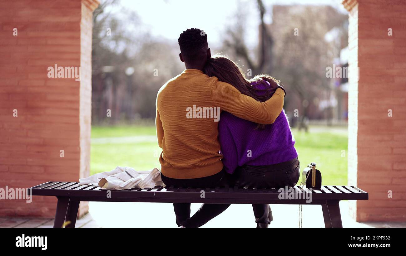 Friend embracing girlfriend, black man putting arm around girl sitting ...