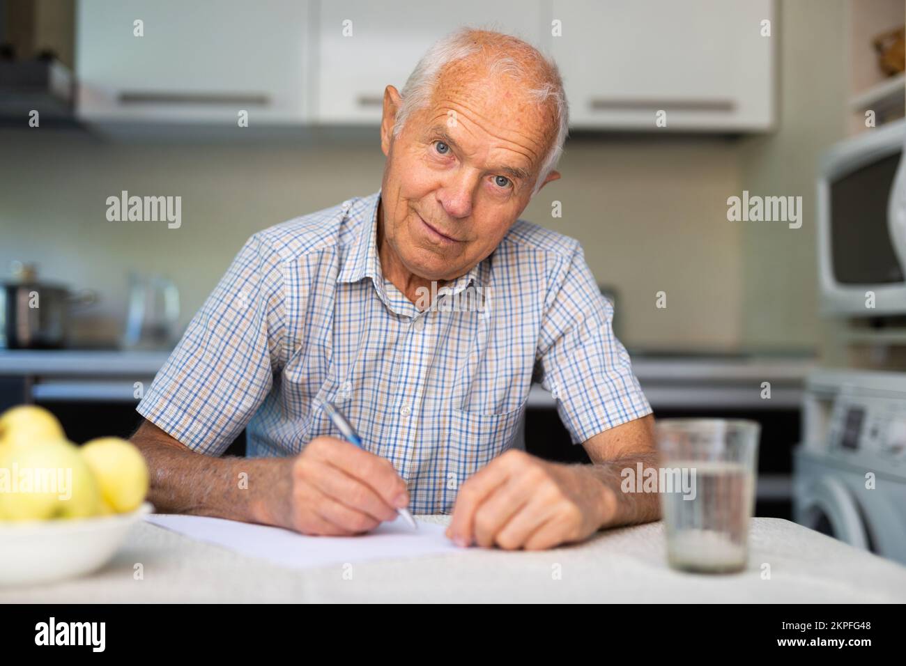Man writing letter on paper while sitting in kitchen at home Stock ...