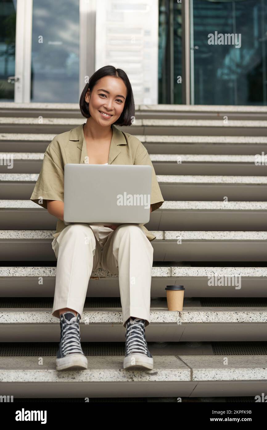 Young asian woman using laptop outdoors. Cute girl student with ...