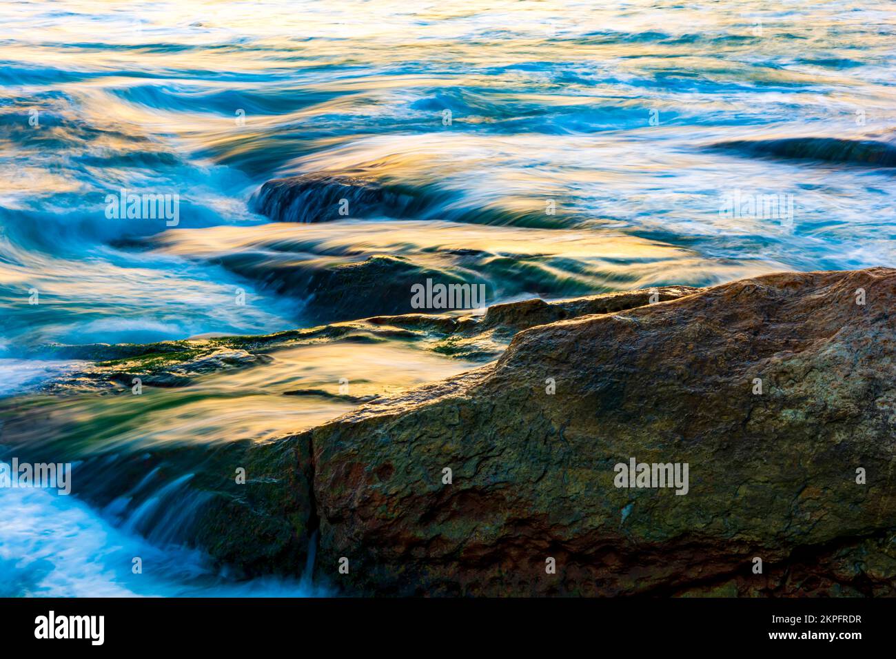 Sea water blurred by the movement and dripping between the stones with ...