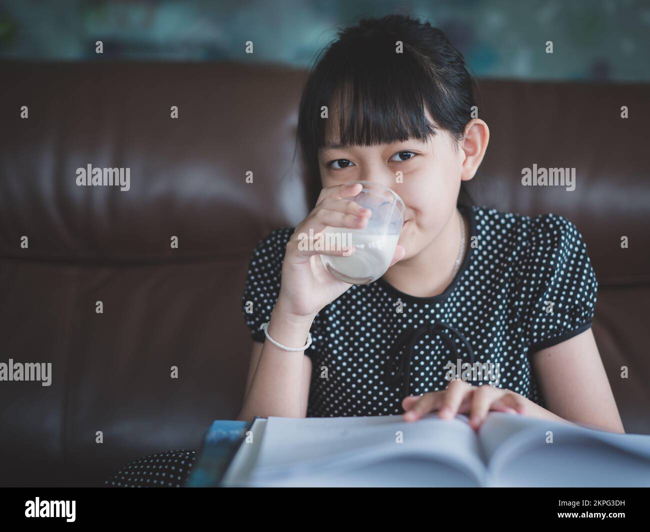 Little girl drinking milk after reading and doing homework inside her ...