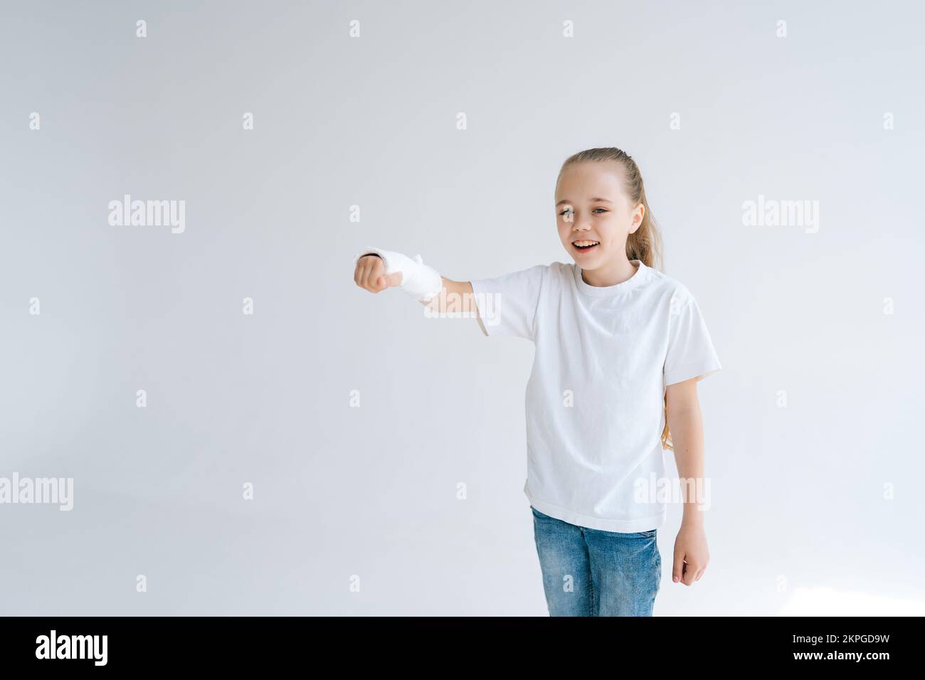 Portrait of positive little girl with broken hand wrapped in white ...
