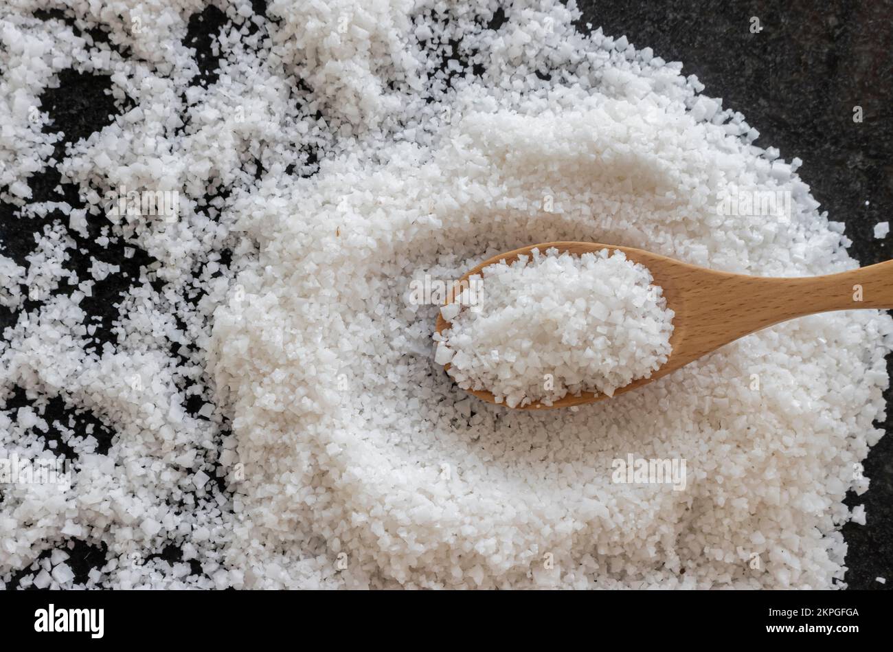 A spoonful of rock salt on the kitchen counter. Isolated on black and ...