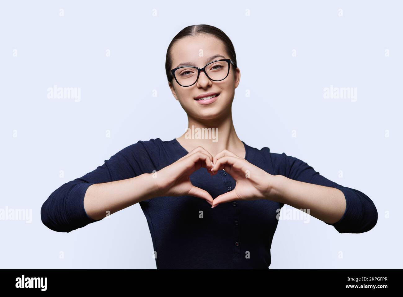 Young Smiling Female Showing Heart Gesture With Fingers White