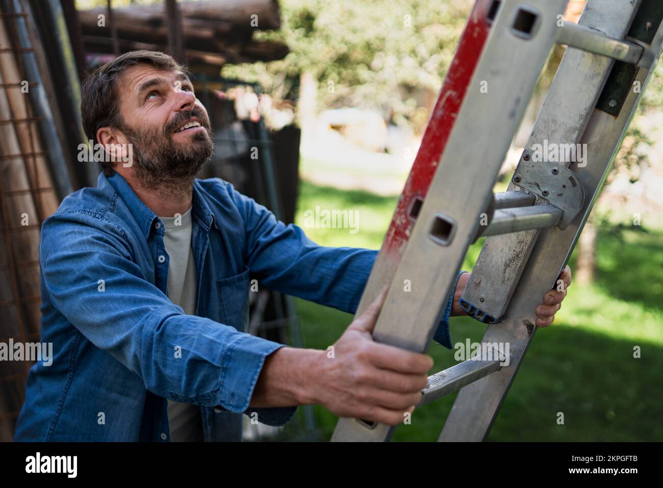 Side view of mature man climbing up the ladder Stock Photo - Alamy