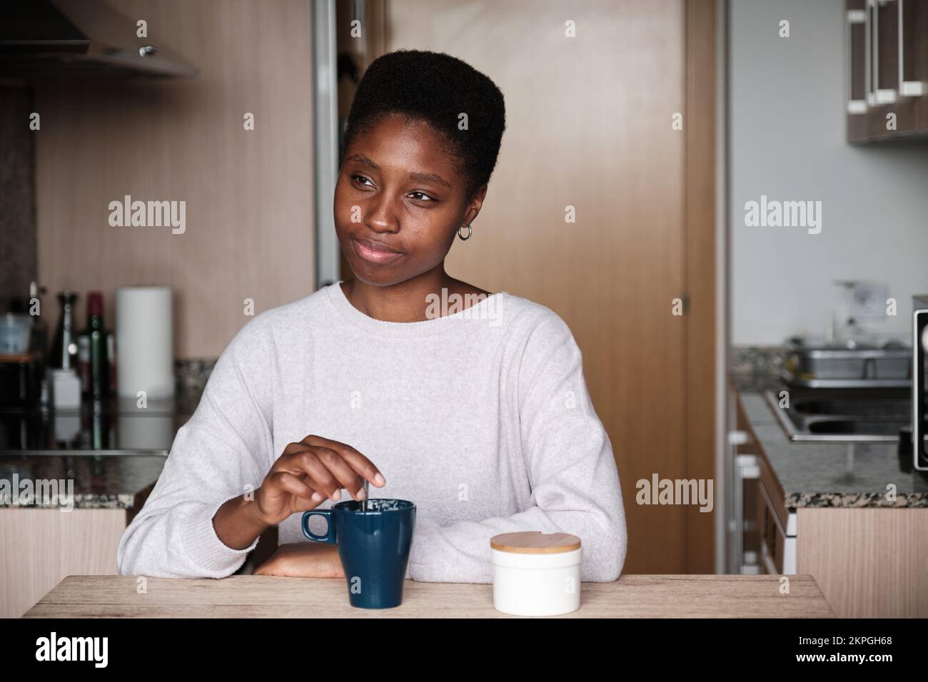 Dreamy African American female sitting in kitchen stirring tea Stock ...