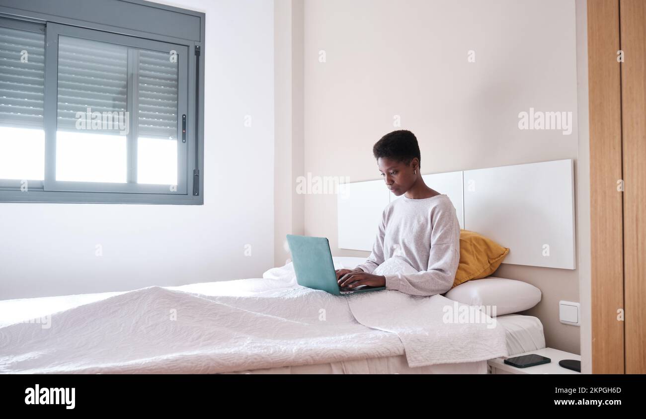 Focused female freelancer working on computer in bedroom Stock Photo ...