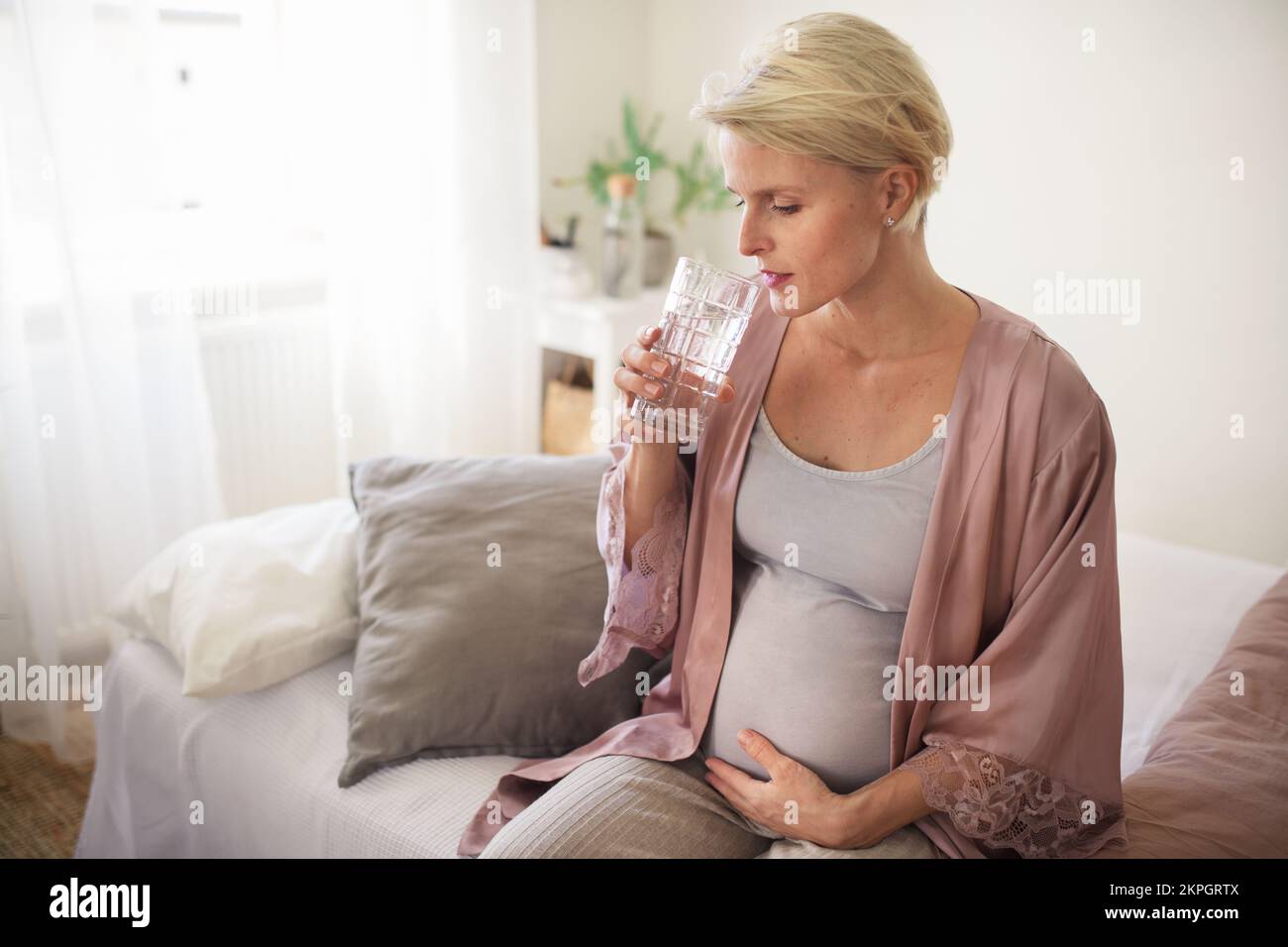 Pregnant woman drinking in her bed, at morning. Healthy lifestyle and ...